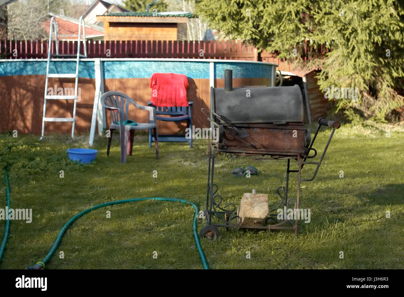 Barbecue in front and swimming pool in the background, outdoor sunset ...