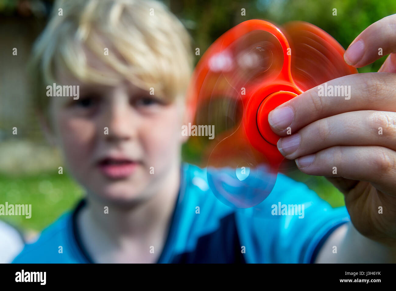 A young boy plays with an orange fidget spinner toy Stock Photo - Alamy