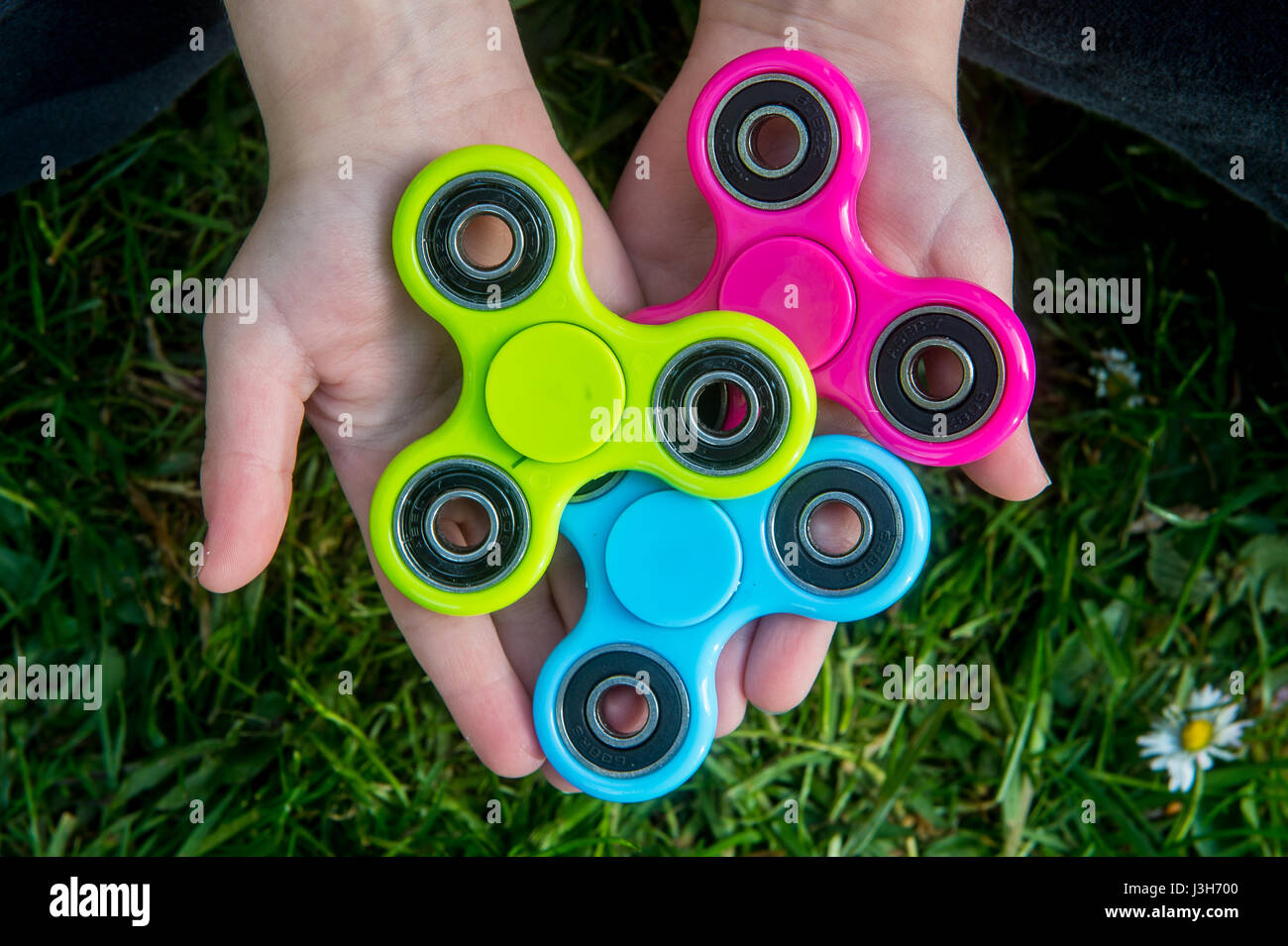 A young boy holds a green blue and pink fidget spinner Stock Photo - Alamy