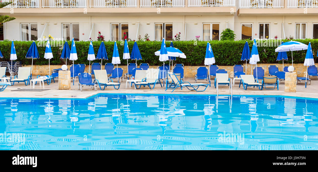 Relax and sunbathe by pool with clear blue water in Resort hotel. Empty ...