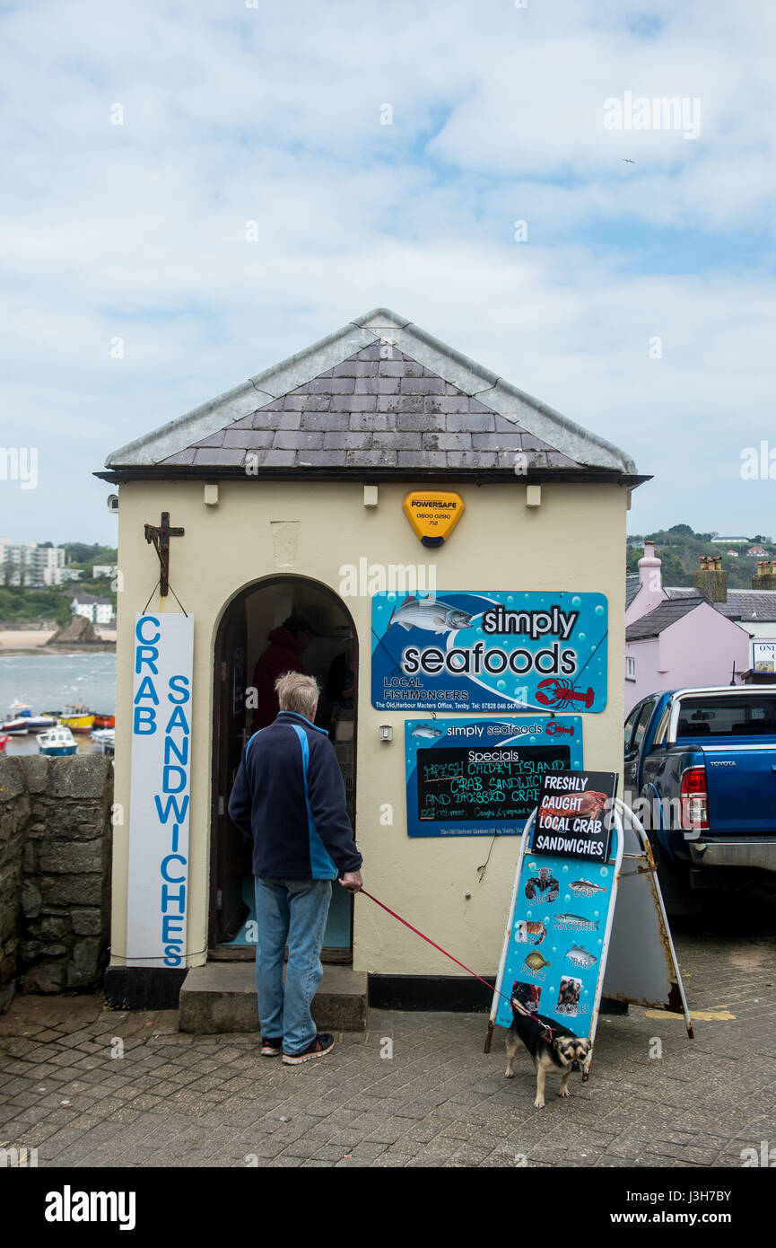 A man stands in the doorway of a seafood shop at Tenby, Pembrokeshire ...