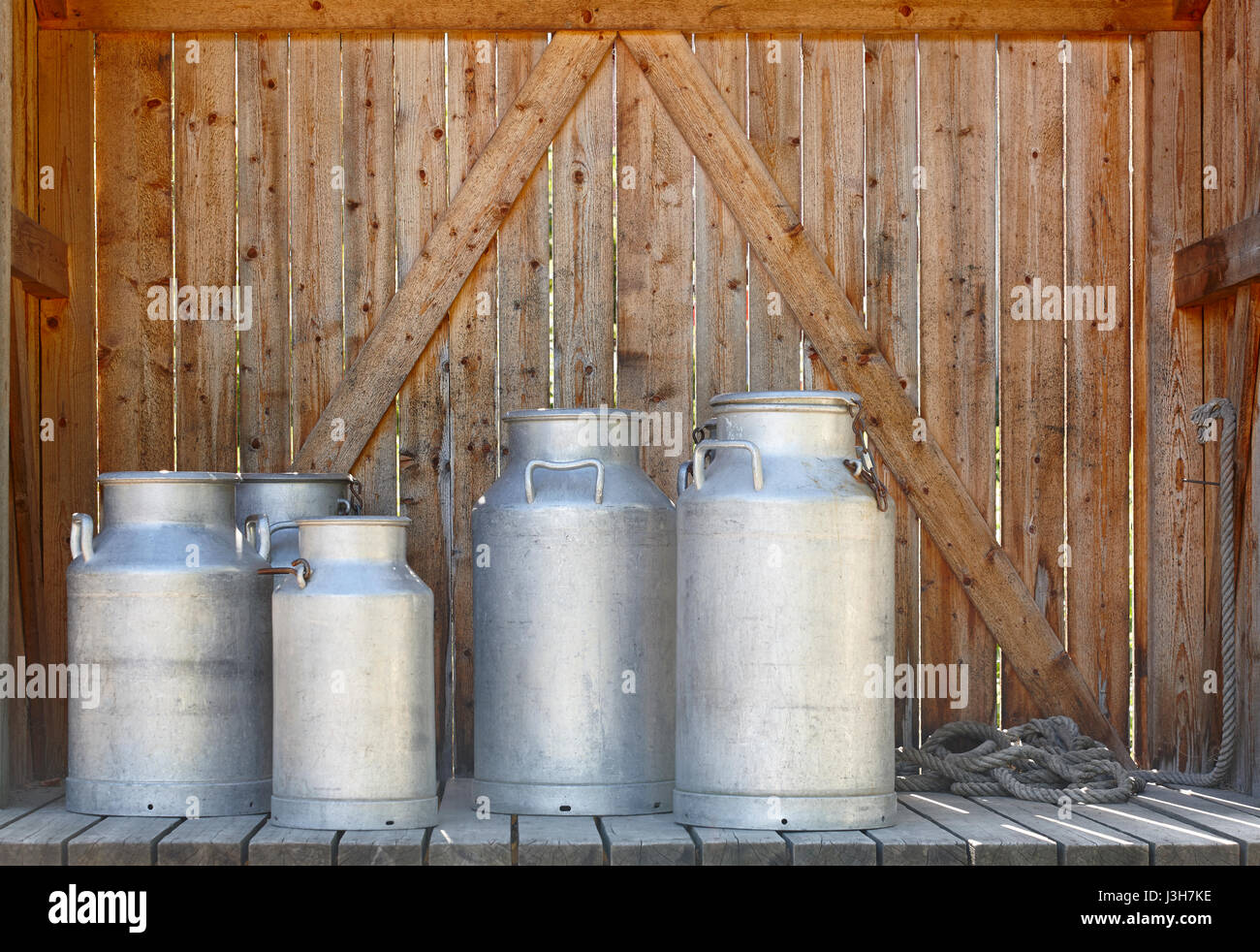 Metallic milk containers on a wooden background. Farming. Horizontal ...