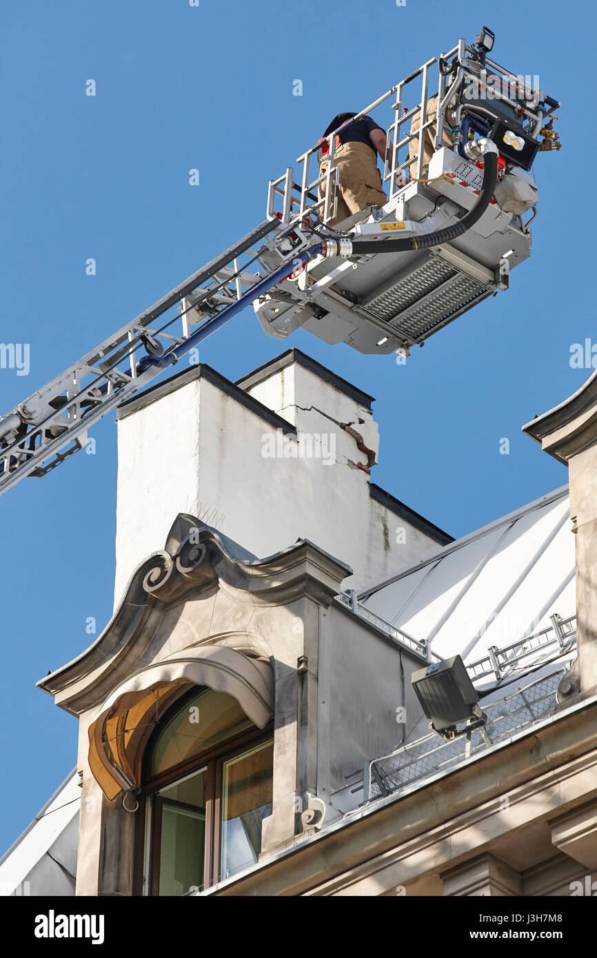 Firemen on a crane fixing a structural building fissure. Working people ...