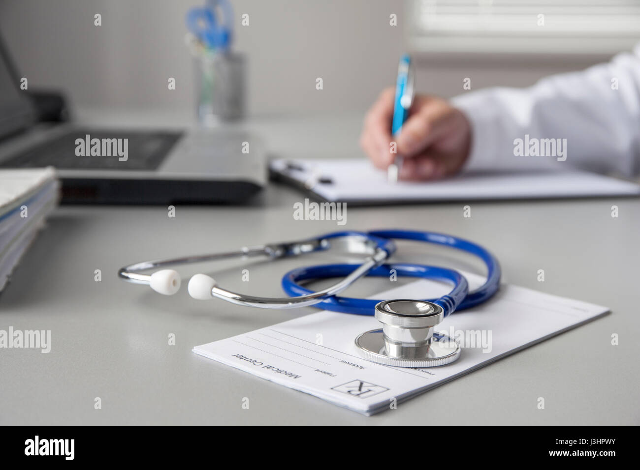 Doctor is filling out report forms after medical examination in his ...