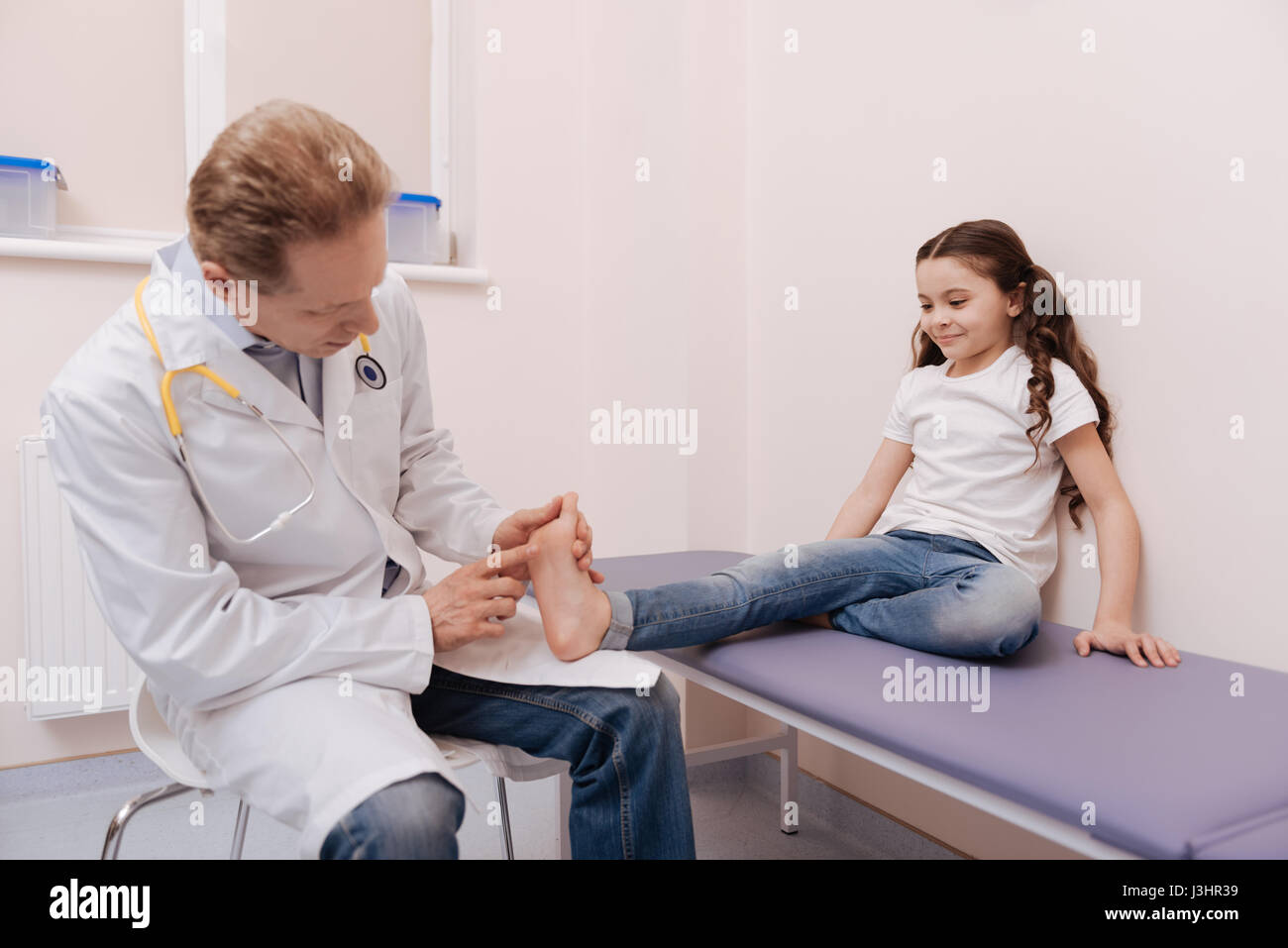 Little toes. Cute nice young girl paying a visit to specialist and ...