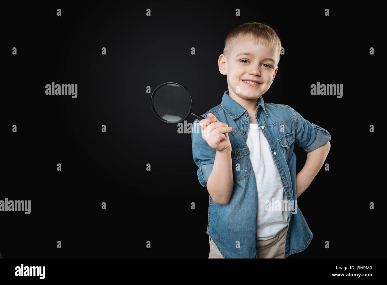 I am clever. Handsome boy keeping smile on his face holding magnifying ...