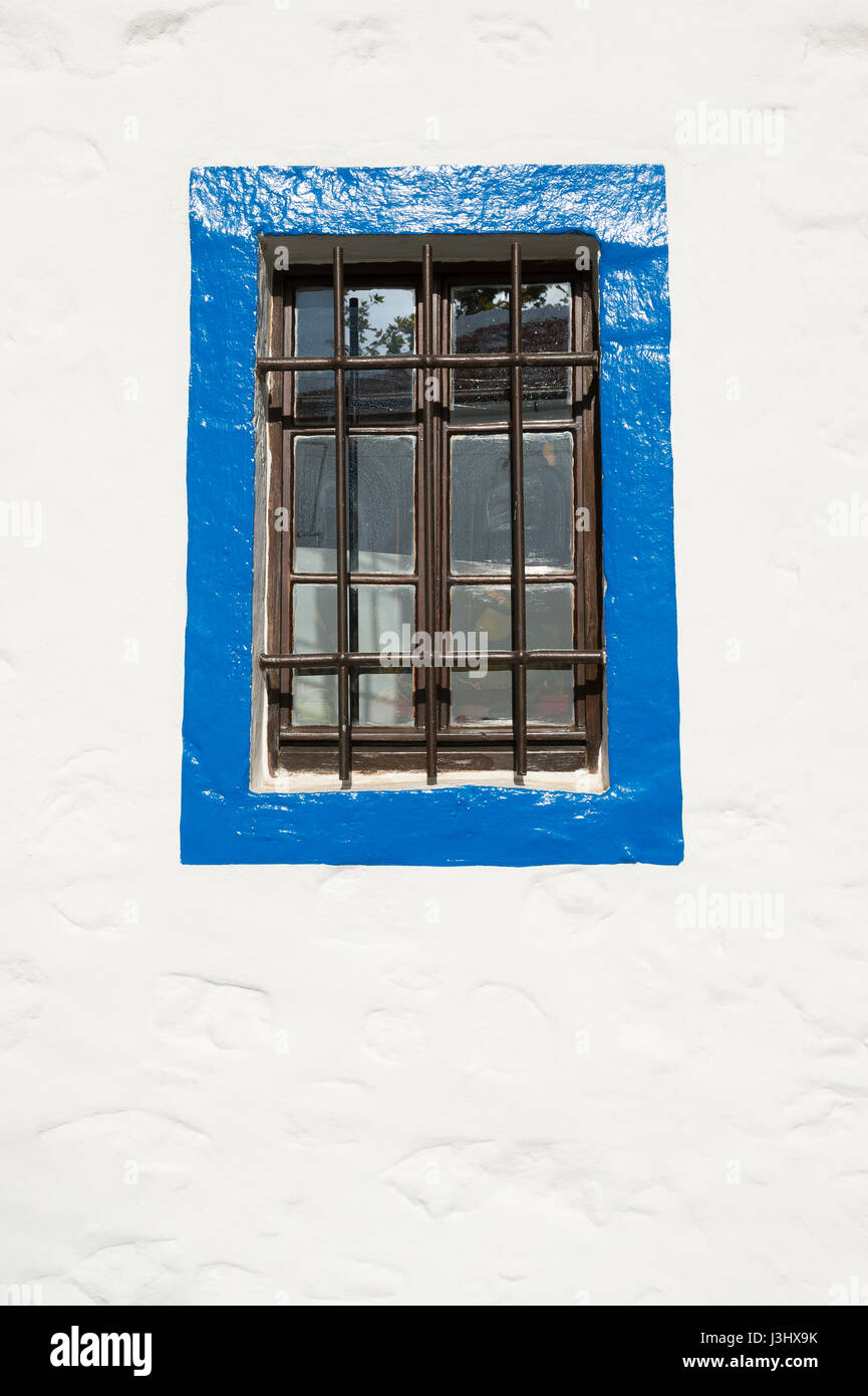 Traditional window with iron bars framed by blue painted border in ...