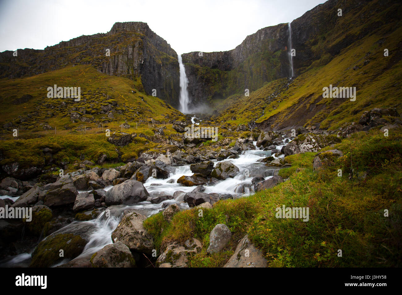 Cold water in Iceland. Waterfall in rocky mountains. Fresh and green ...