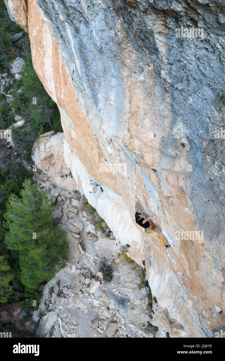 Outdoor sport activity. Rock climber ascending a challenging cliff ...