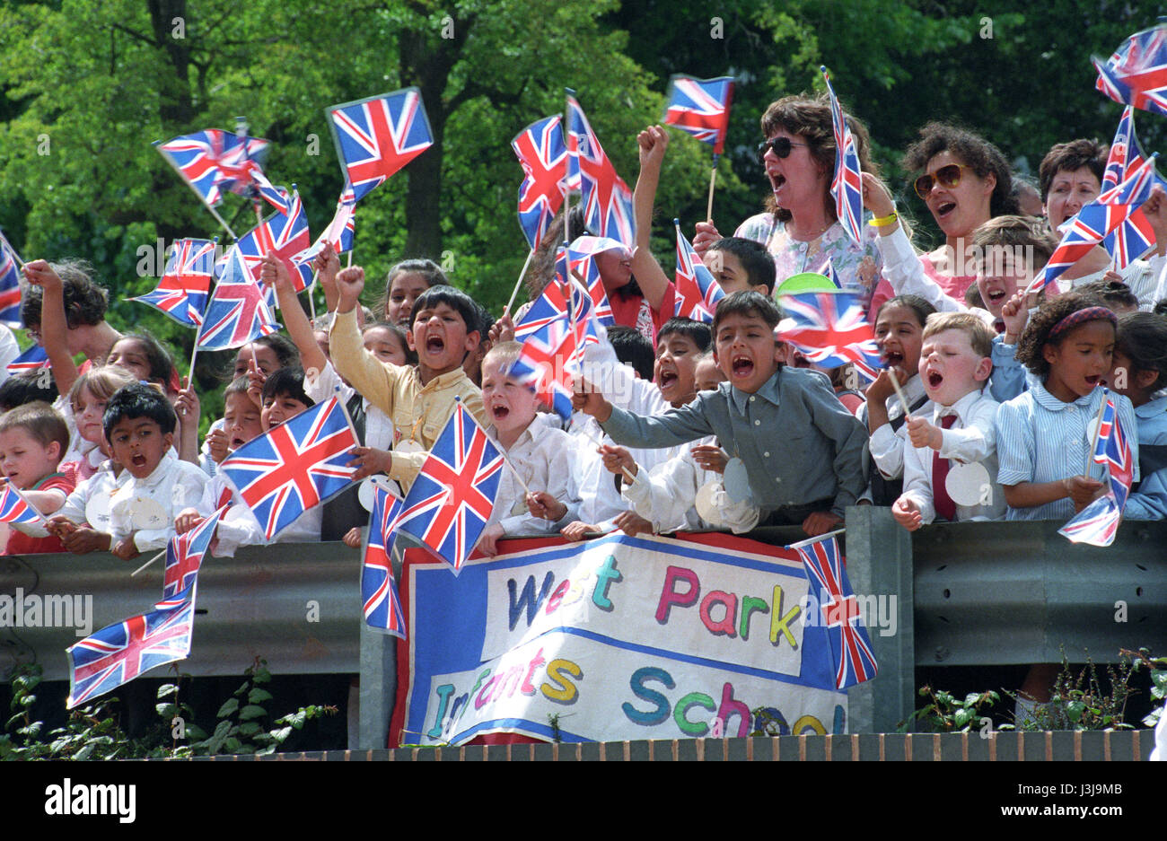 School children cheering and waving Union Jack flags for a royal visit ...