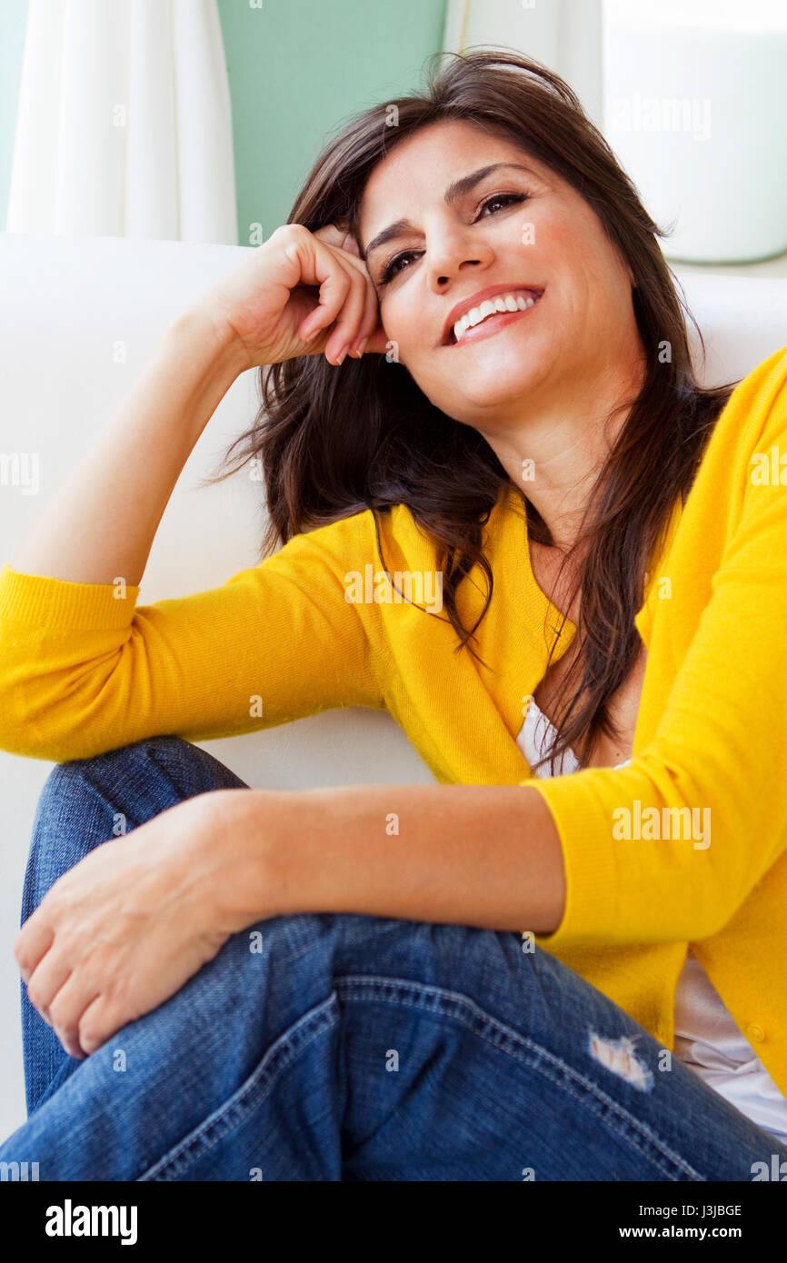 Beautiful woman smiling sitting on a sofa Stock Photo - Alamy