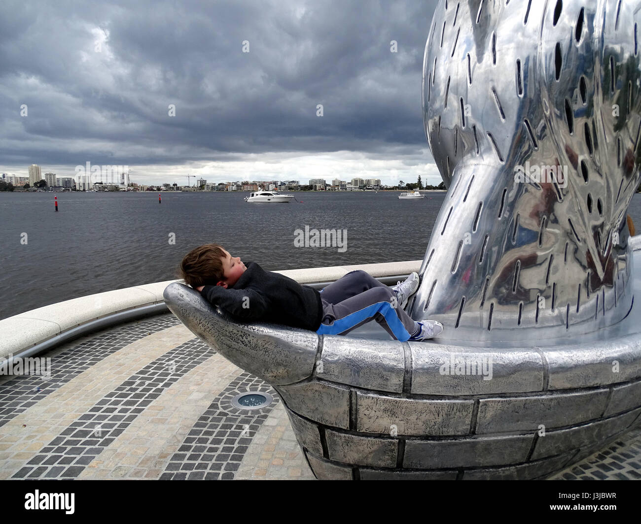 Young Boy resting on a public artwork Stock Photo - Alamy