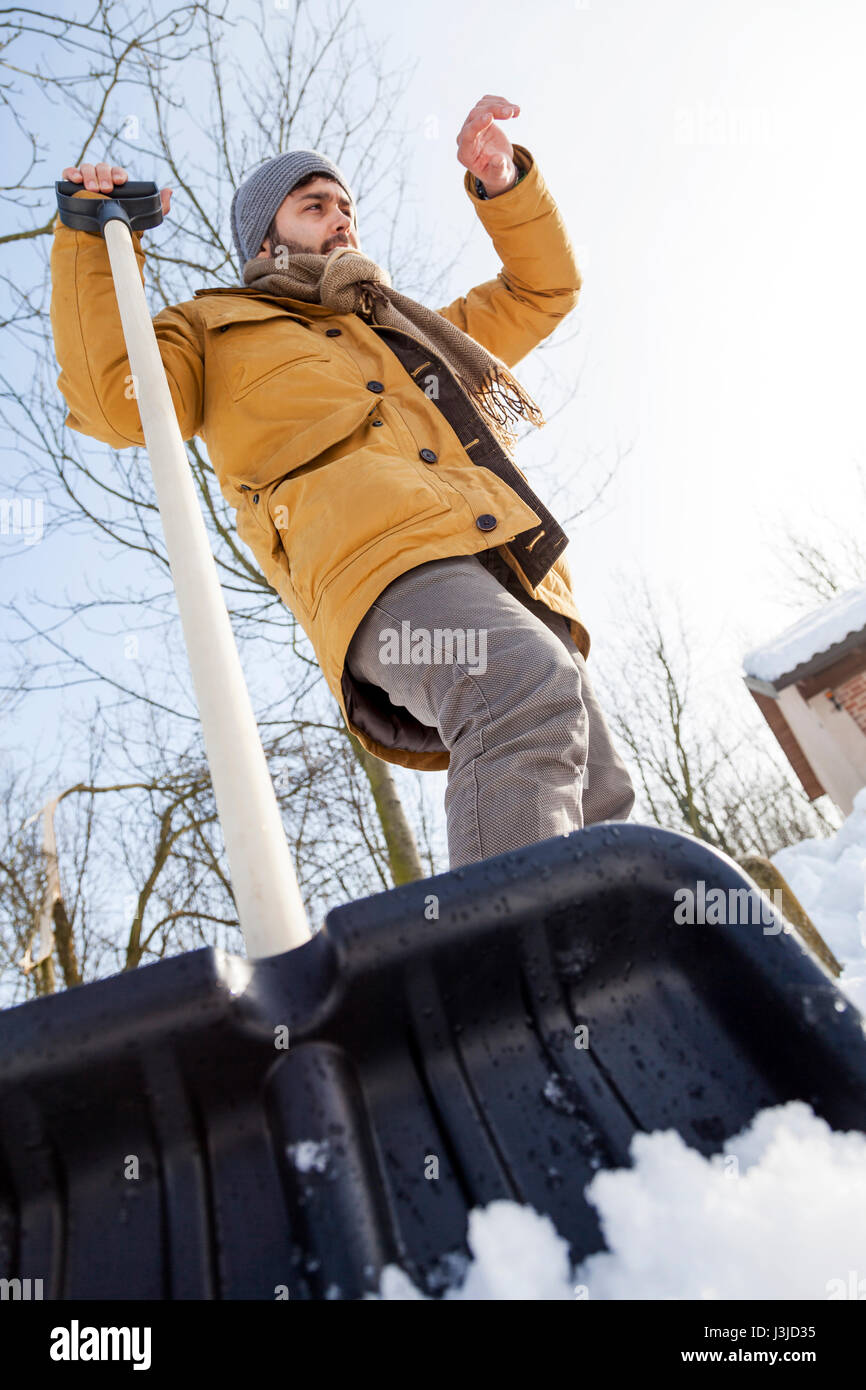 young man shoveling snow near a small wood Stock Photo - Alamy