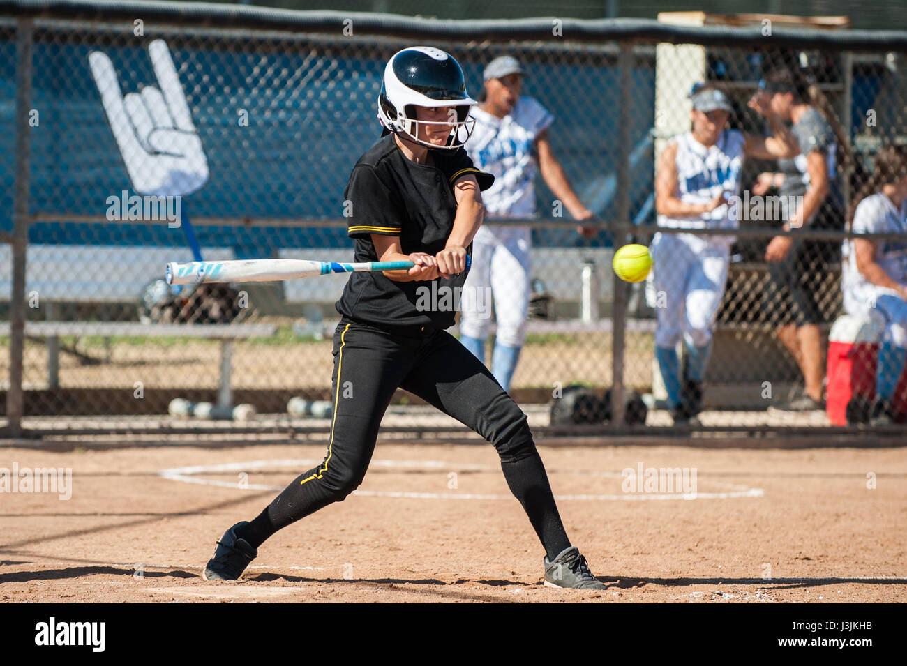 Black uniform fast pitch softball batter with eyes in incoming ball ...