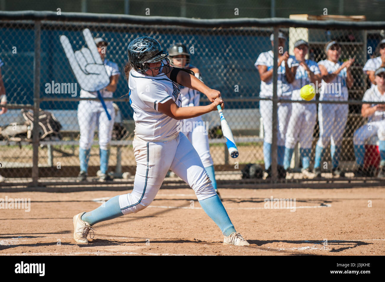 White uniform fast pitch softball batter watching ball fly after ...