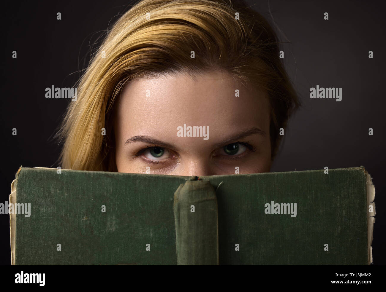 Young woman with old book on a dark background . On cover free space ...