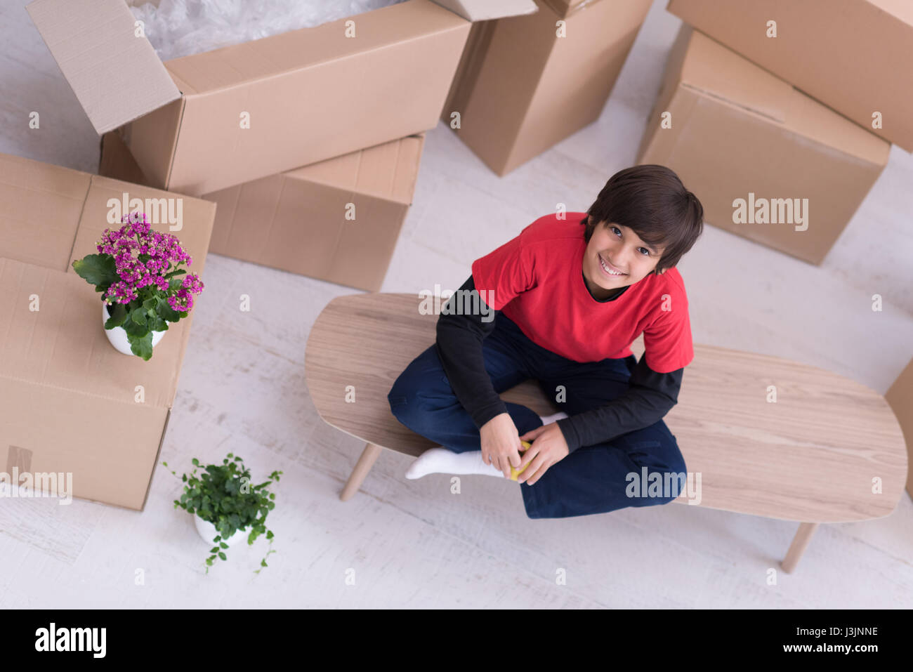 happy little boy sitting on the table with cardboard boxes around him ...