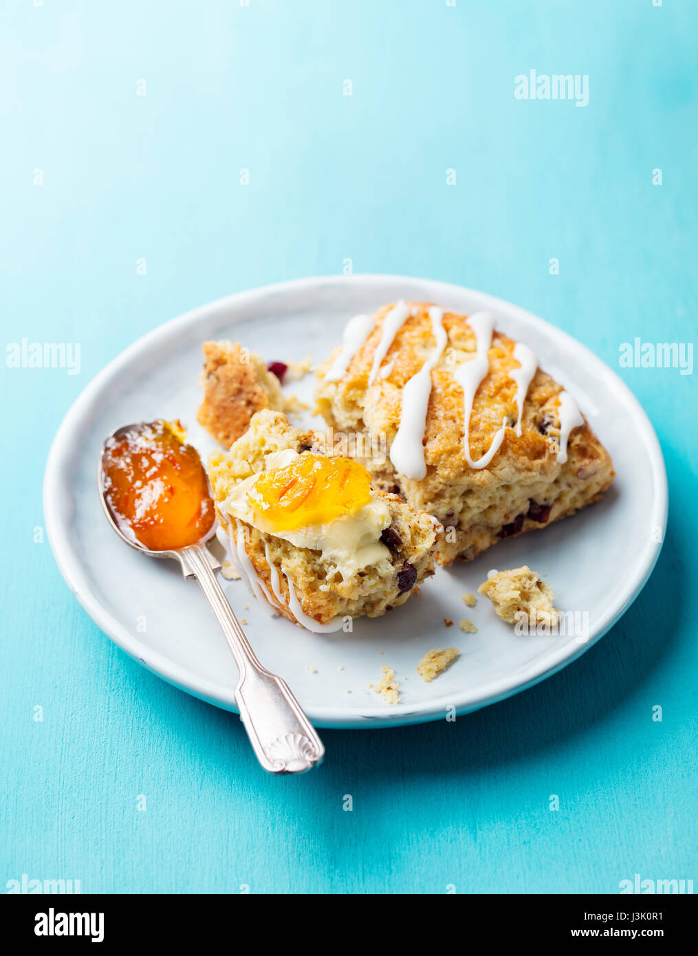 Scone with jam and butter on plate. Blue background Stock Photo - Alamy