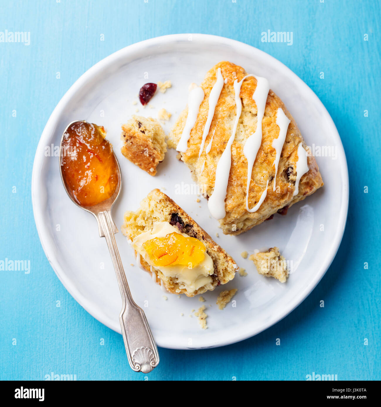 Scone with jam and butter on plate. Blue background. Top view. Copy ...