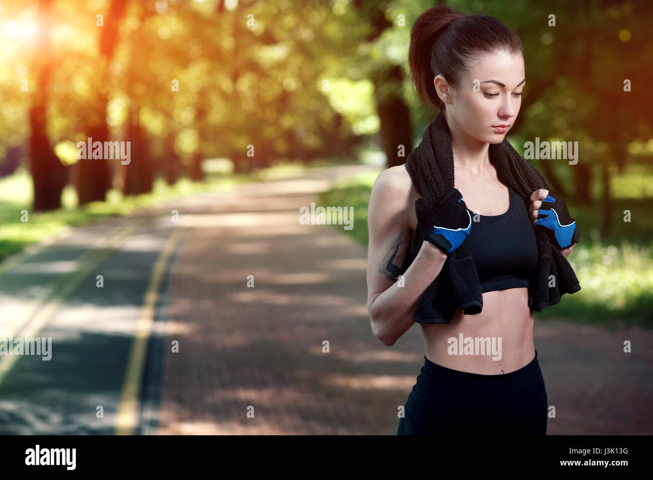 Young beautiful strong slender woman doing sports in summer park and ...