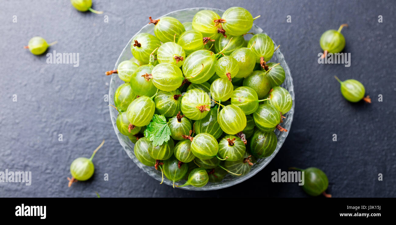 Fresh gooseberries in glass bowl on black stone slate background. Top ...