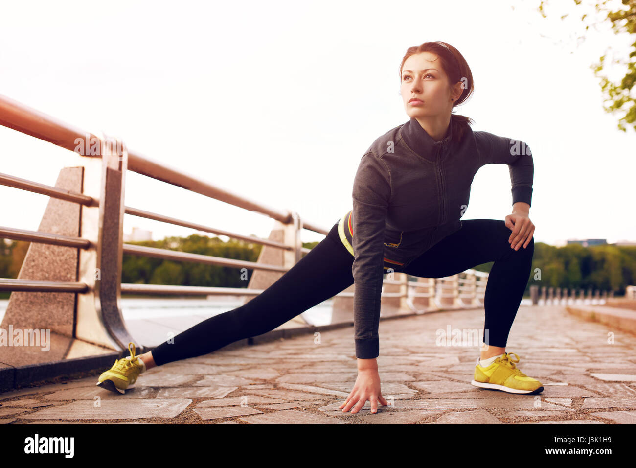 Female runner with beautiful figure doing stretching exercise before ...