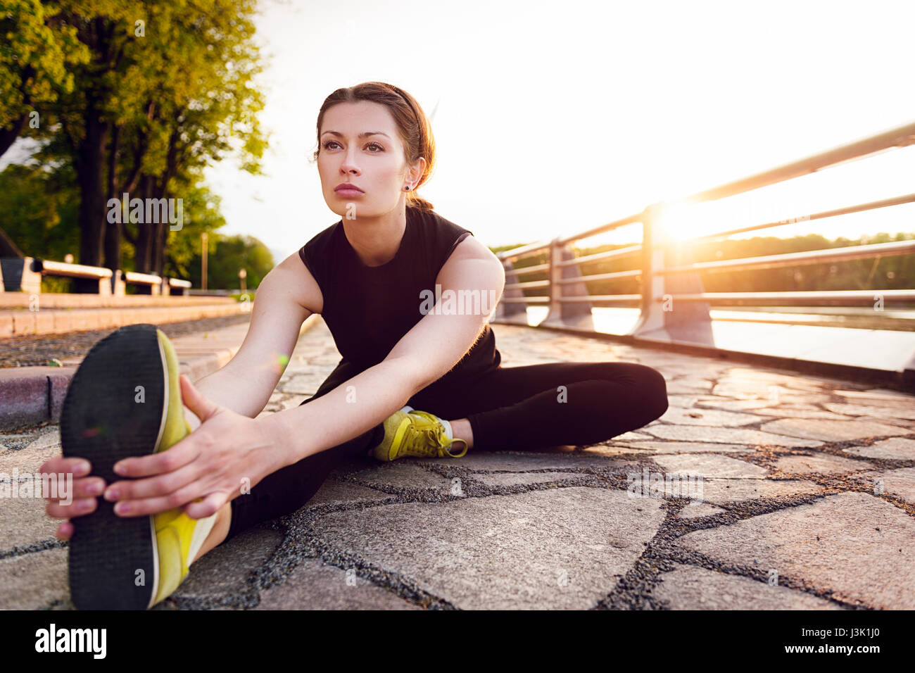Yong female runner with beautiful figure doing stretching exercise ...