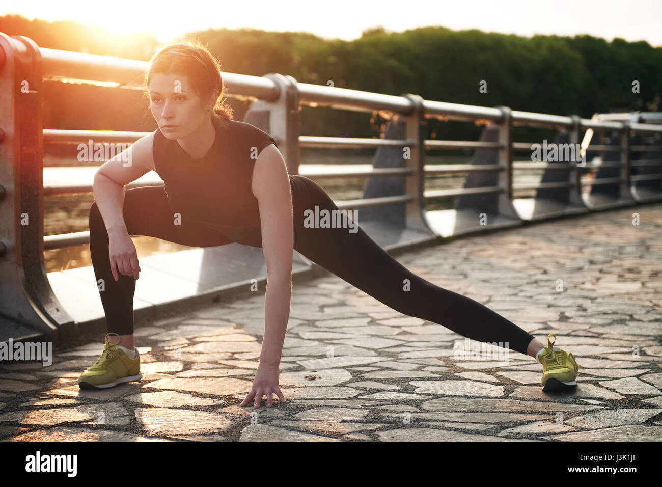 Yong female runner with beautiful figure doing stretching exercise ...