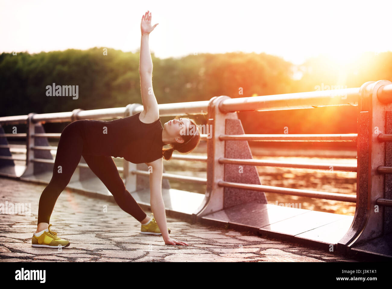 Young beautiful strong slender woman doing sports in summer park and ...