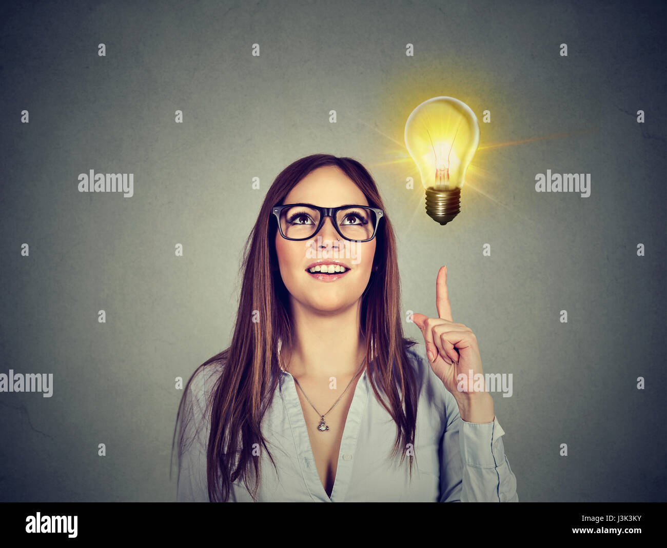 Portrait of woman pointing at bright light bulb. Success growing ...