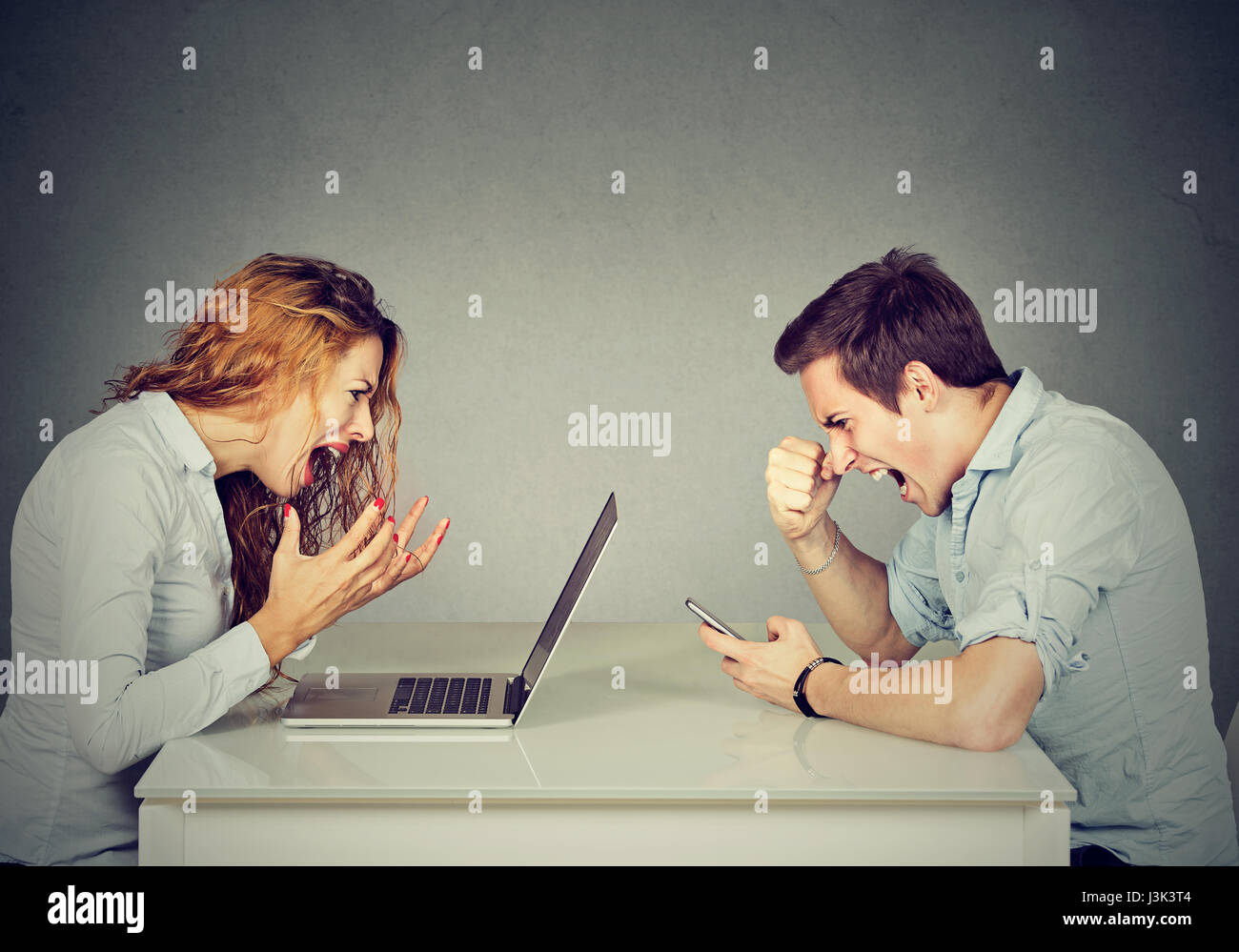 Stressed business woman with laptop sitting at table with angry man ...