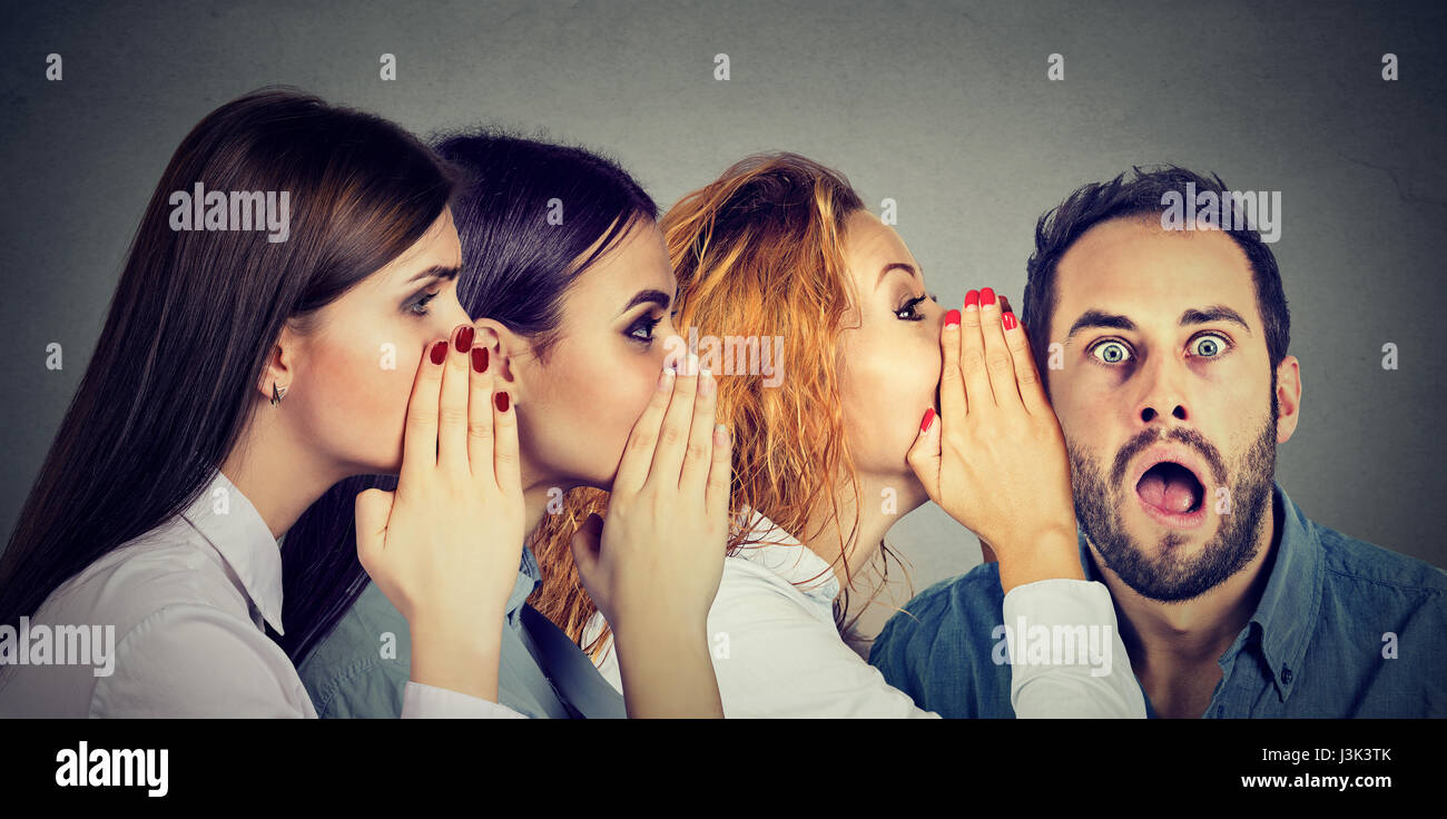 Three young women whispering each other and to the shocked astonished ...