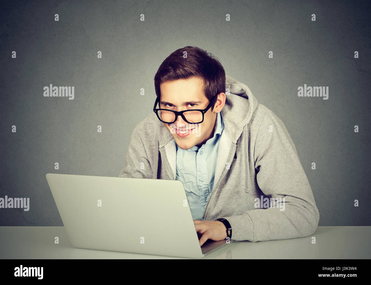 Young sly devious man using a laptop plotting server sabotage Stock ...