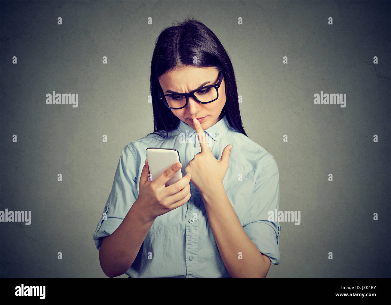 Clueless perplexed looking girl having troubles with her new smartphone. Complicated technology ...