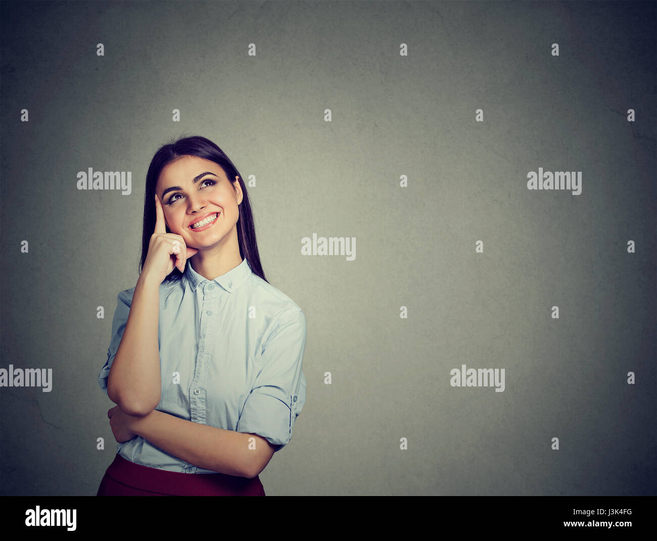 Portrait happy woman thinking looking up smiling isolated on gray wall ...