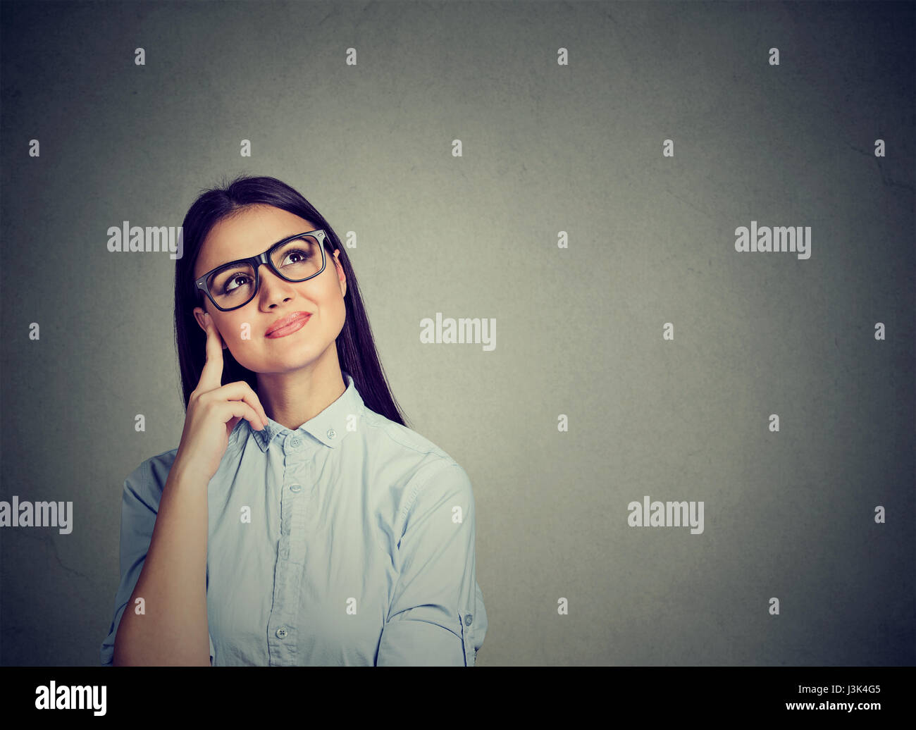 Portrait happy woman thinking looking up isolated on gray wall ...