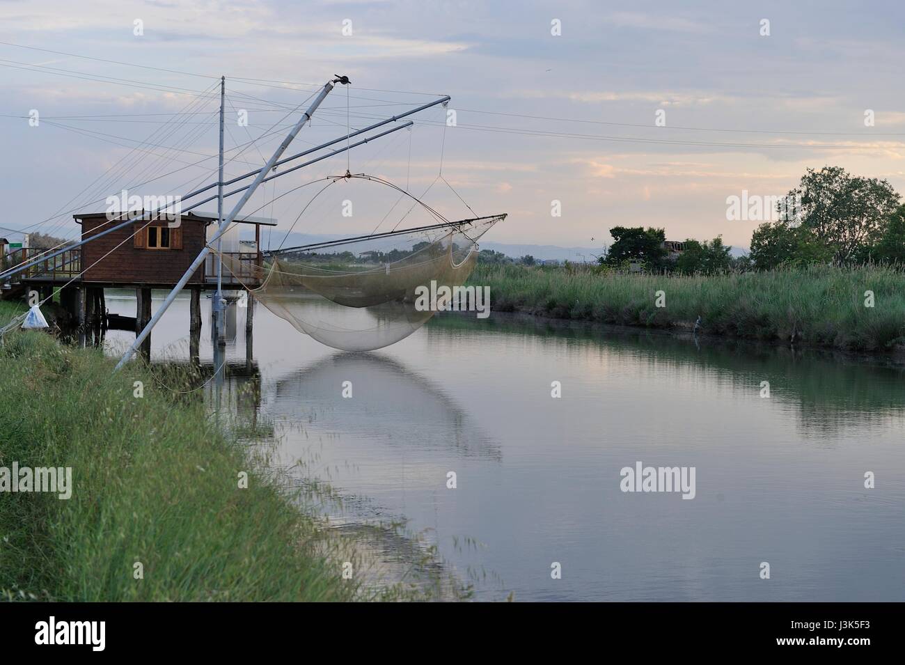 Fishermen's shack with fishing net on the Cervia salt marsh canal ...
