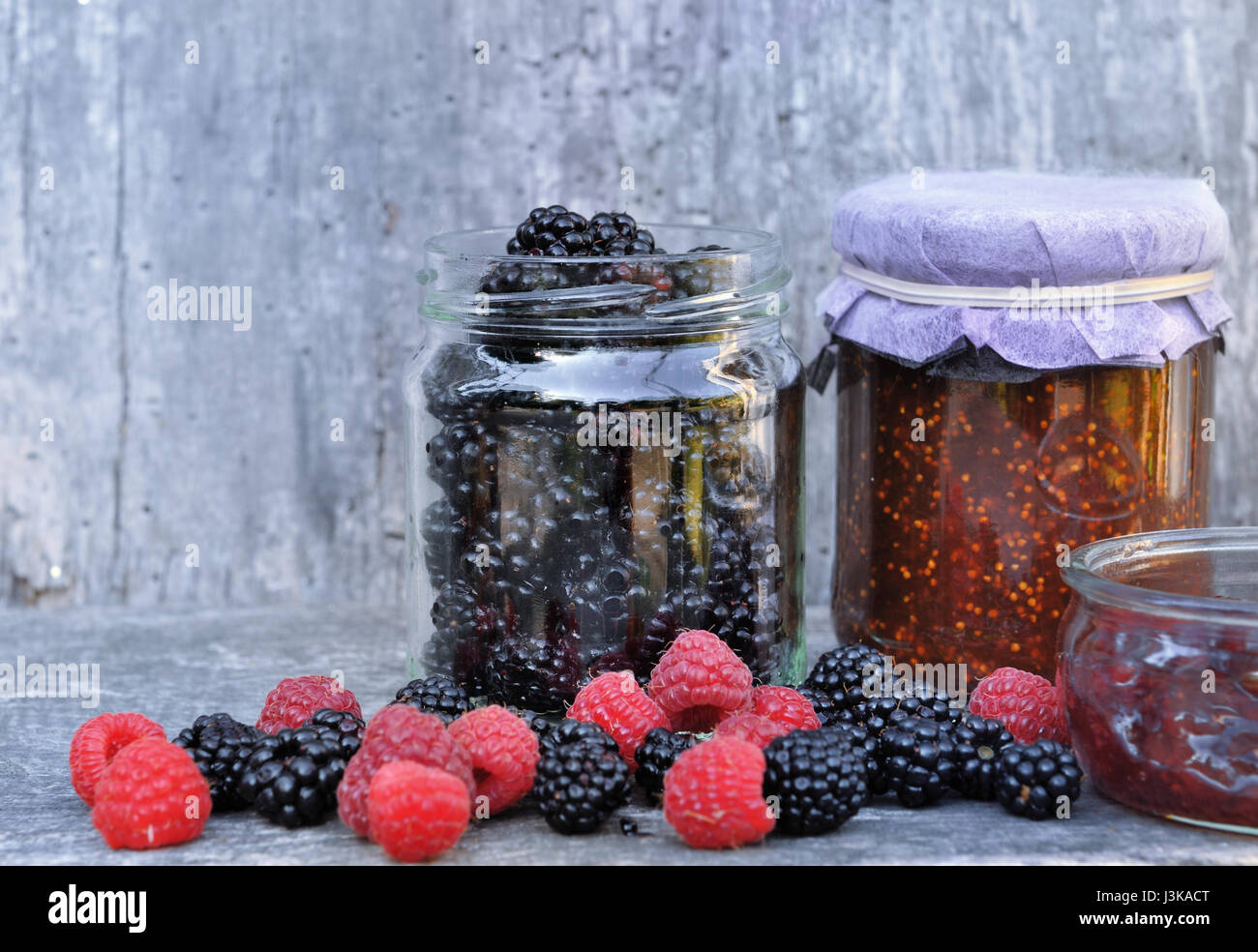 pot of jam and red fruits on wooden background Stock Photo - Alamy