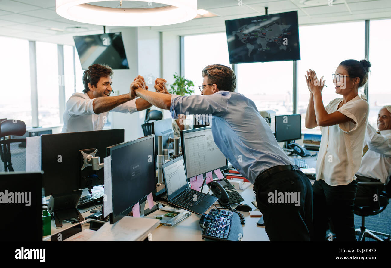business team cheering at good news as they congratulate each other on ...