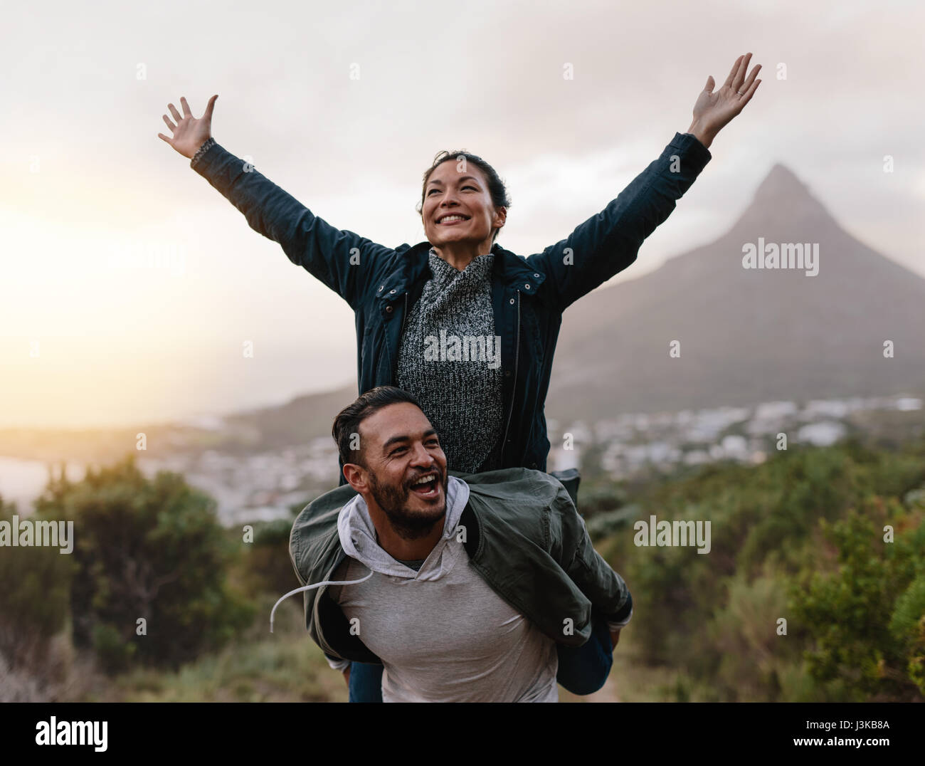 Happy young man carrying his girlfriend with her arms raised. Couple ...