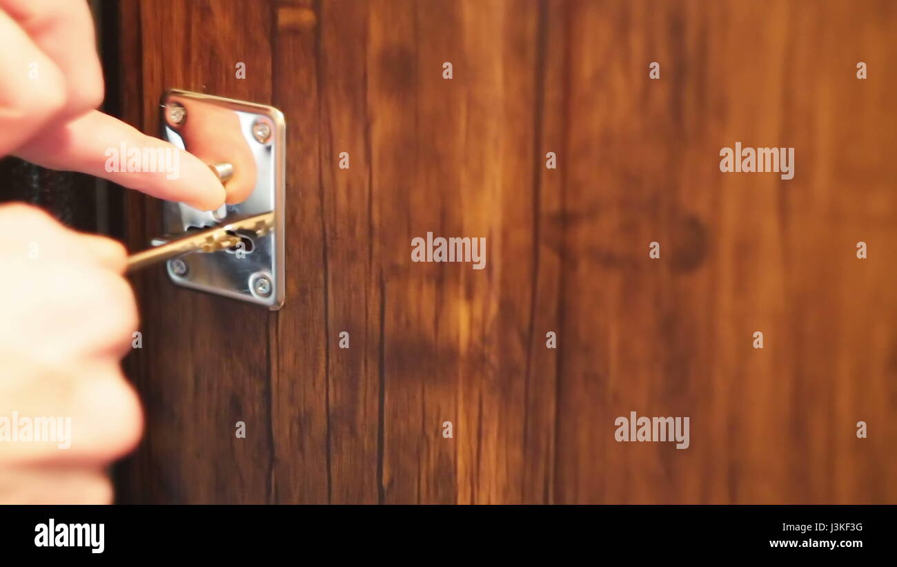 man's hand opens a lock with a key in the door Stock Photo - Alamy