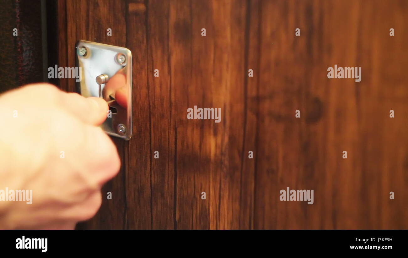 man's hand opens a lock with a key in the door Stock Photo - Alamy