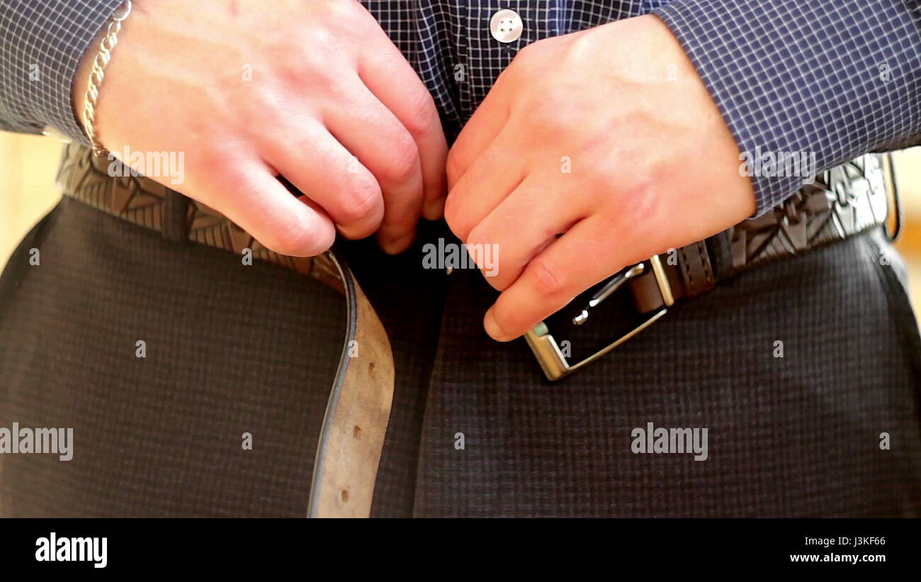Man in blue shirt buckling undoes the belt on his pants Stock Photo - Alamy
