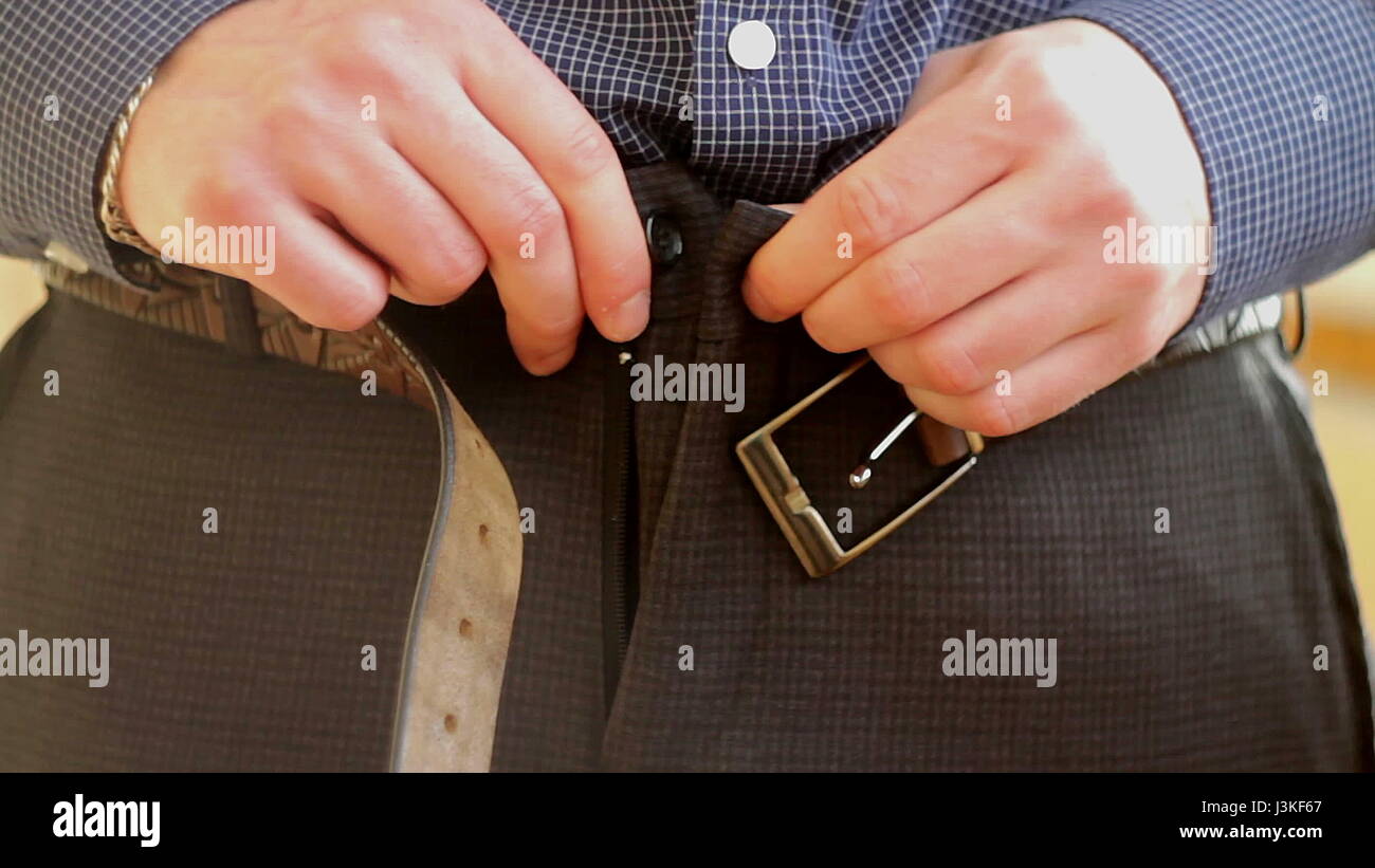 Man in blue shirt buckling undoes the belt on his pants Stock Photo - Alamy