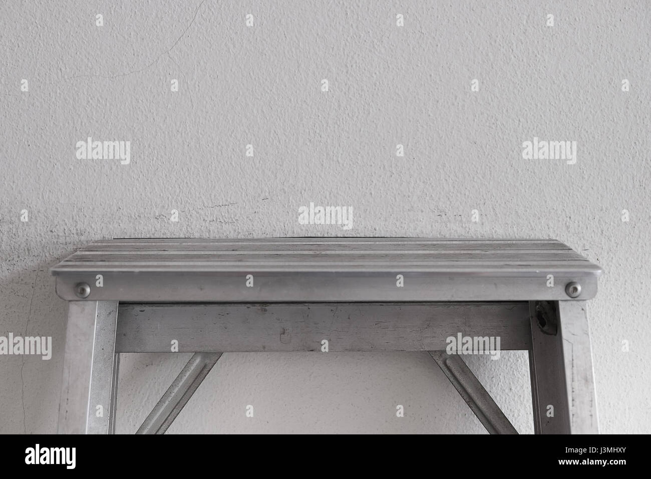 Aluminum ladder on the gray wall, room interior Stock Photo - Alamy