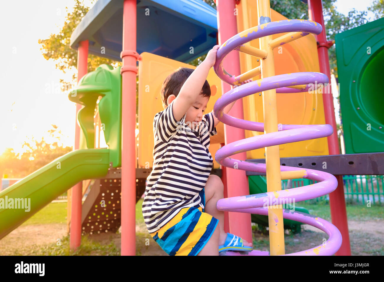 Active little child playing climbing spring metal at school yard ...