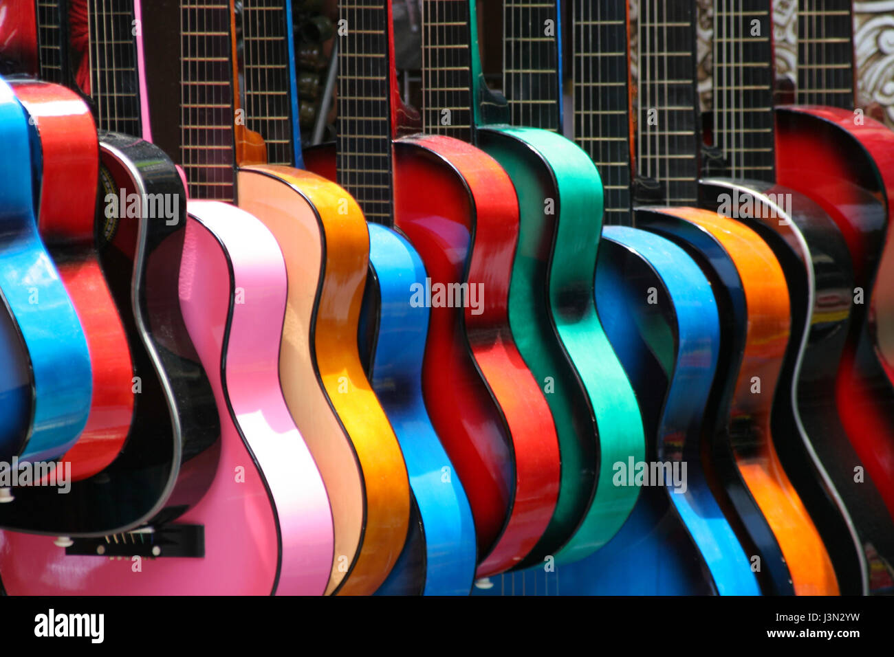 Horizontal view of the colorful children's guitars lined up for sale in ...