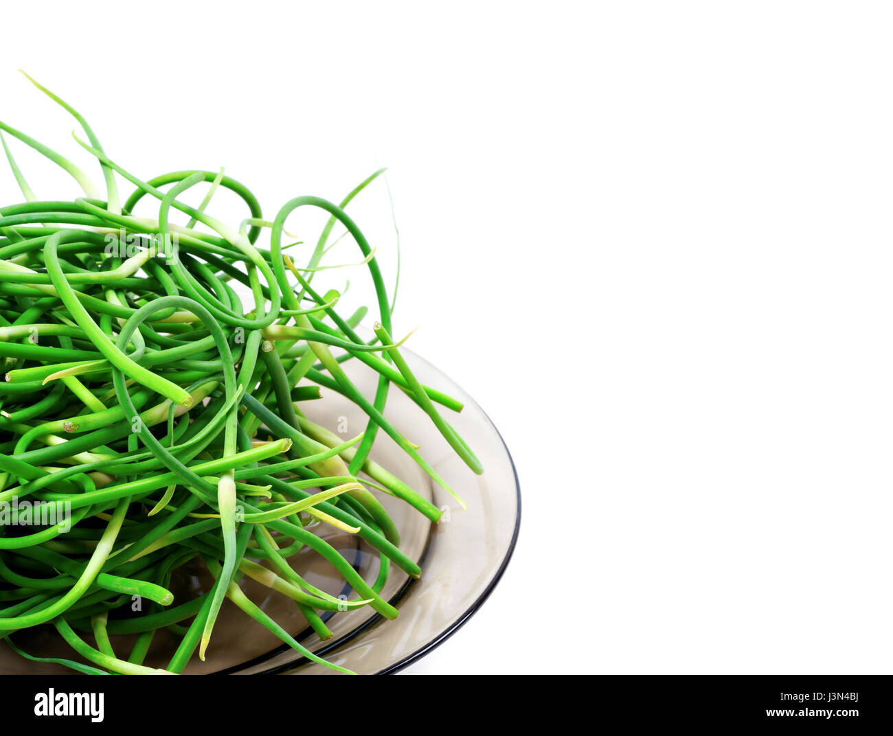 Fresh garlic scapes on glass plate. Isolated on white background with ...