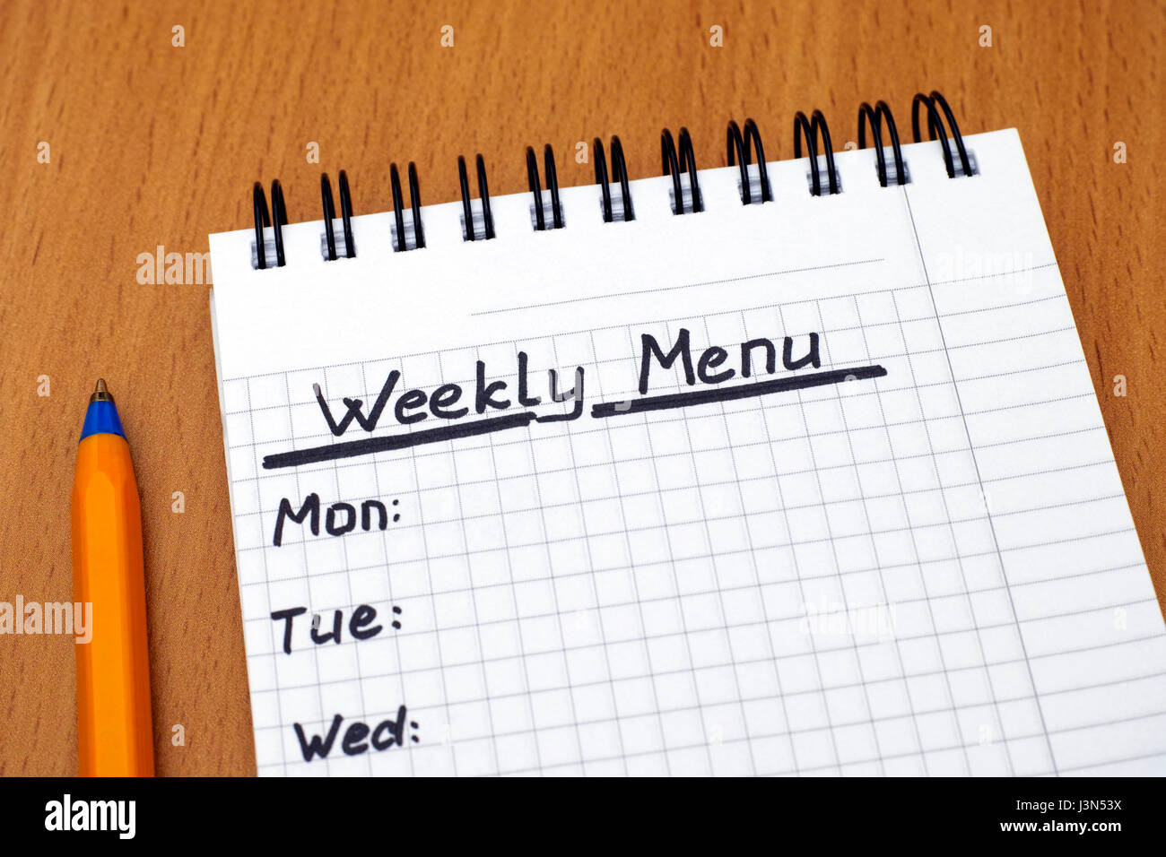 Words Weekly Menu written on white note pad with ballpoint pen. Close ...