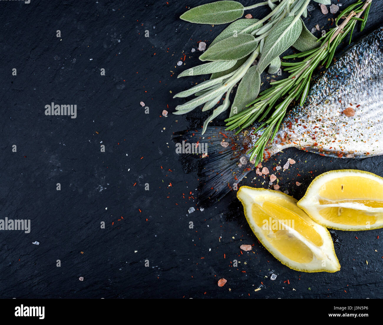 Tail of fresh raw Dorado or sea bream fish on black slate stone board ...